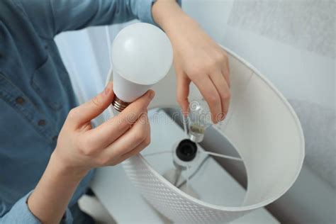 Woman Changing Incandescent Light Bulb For Fluorescent One In Lamp At Home Closeup Saving