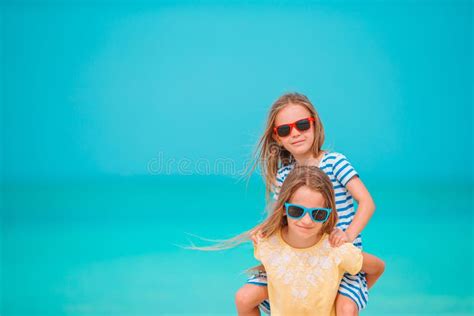 Two Little Happy Girls Have A Lot Of Fun At Tropical Beach Playing
