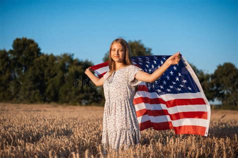 Portrait Of A Beautiful Smiling Girl With Flag Of Usa In The Field Of
