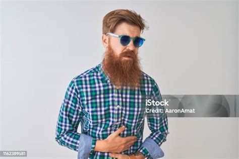 젊은 빨간 머리 아일랜드 남자 캐주얼 셔츠와 선글라스 위에 고립 된 흰색 배경 위에 손에 위장에 메스꺼움 고통 스러운 질병