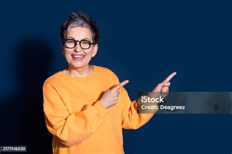 예쁜 고위 여성 포인트 빈 공간 착용 유행 노란색 복장 진한 파란색 배경 배경 절연 사진 초상화 50 54세에 대한 스톡 사진 및 기타 이미지 Istock
