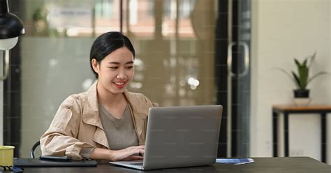 웃고 있는 여성 그래픽 디자이너는 사무실 책상에서 노트북 컴퓨터로 작업하고 있다 사진 Unsplash의 태국 이미지