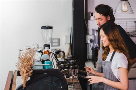 젊은 아시아 남자와 여자 바리스타 는 미소 얼굴로 커피 숍의 바 카운터에서 고객에게 제공되는 커피 컵을 만드는 앞치마를 착용합니다 카페와 커피 숍 중소 기업의 개념 빈티지