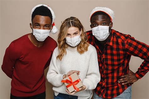 산타 클로스 모자와 의료 마스크크리스마스 선물을 들고 카메라를보고 쾌활한 다양한 젊은이의 그룹 12월에 대한 스톡 사진 및 기타