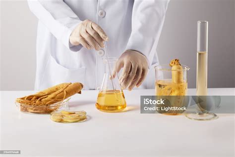 흰색 질감의 앞 사진 연구원이 비커 옆에 놓인 삼각 플라스크에 노란색 용액을 휘젓는 유리 막대기를 들고 흰색 테이블 위에 인삼 측정 실린더와 페트리 접시를 들고 있습니다