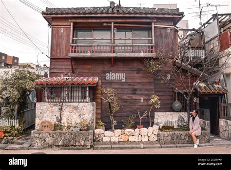 Girl Sitting In Front Of A Traditional Japanese Wooden House In Naha