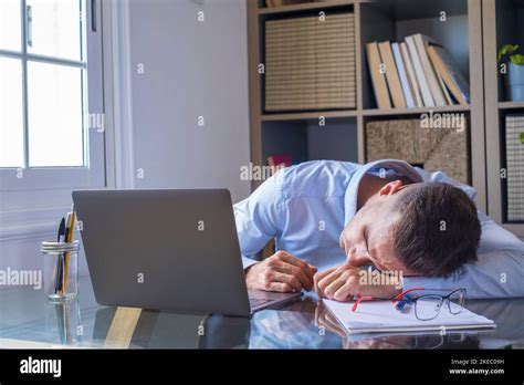 tired businessman is sleeping at his work desk with laptop computer