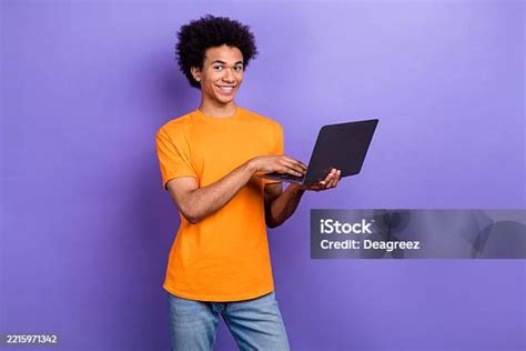 잘 생긴 남자 착용 트렌디 한 오렌지 티셔츠 홀드 노트북 맥북 프로 로고 브랜드 광고 바이올렛 컬러 배경에 고립 된 사진 T 셔츠에 대한 스톡 사진 및 기타 이미지 Istock
