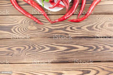 오래 된 갈색 나무 소박한 판자에 흰색 세라믹 그릇에 고추의 힙 옆에 흩어져 빨간 Wholes 신선한 익은 칠리 고추 0명에