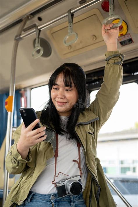 A Positive Asian Female Solo Traveler Using Her Smartphone While