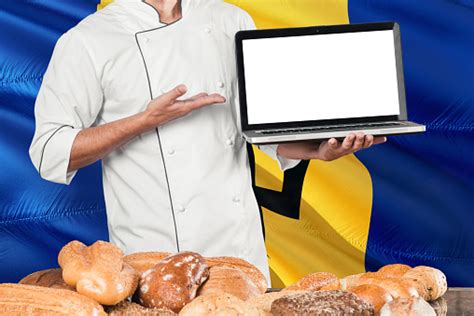바베이도스 국기와 빵 배경에 노트북을 들고 바르 바 디안 베이커 요리사가 복사 공간에 대 한 균일 한 포인팅 빈 화면을 착용 고급 요리에 대한 스톡 사진 및 기타 이미지