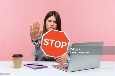 공포에 질린 여성 사무실 노동자가 빨간 교통 표지판을 들고 직장에서 의한 괴롭힘을 차단하면서 손과 함께 중지 제스처를 보여주고