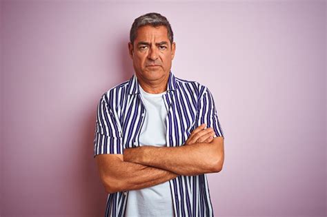 고립 된 분홍색 배경 회의론자 및 긴장 교차 된 팔로 얼굴에 표정을 거부 위에 서 줄무늬 셔츠를 입고 잘 생긴 중년 남자 부정적인 사람 감정에 대한 스톡 사진 및 기타