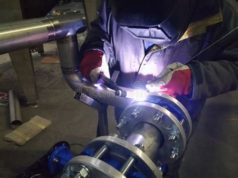 Tig Welder Joining Metal Pipe With Protective Helmet And Gloves Stock