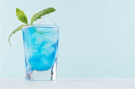 얼음 조각이 있는 블루 큐라소 칵테일 화이트 우드 보드의 고급 샷 글래스의 그린 민트 파스텔 민트 컬러 월 0명에 대한 스톡 사진 및 기타 이미지 Istock