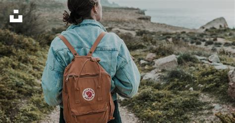 갈색 배낭과 함께 파란색 데님 재킷을 입고 해변 근처 산책로를 걷는 여자 사진 Unsplash의 무료 몰타 이미지