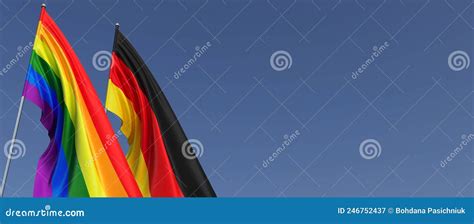 LGBT And German Flags On Flagpole On Blue Background Rainbow Flag Place For Text LGBT