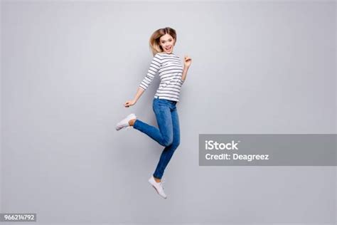 전체 길이 크기 몸 여자의 초상화 매력적인 재미 있고 만화 명랑 한 좋은 귀여운 제기 다리 카메라를 보고 점프 하는 줄무늬 옷에 회색 배경에 고립 오픈 입은 데 날기에 대한