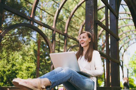 가벼운 캐주얼 옷에 젊은 성공적인 사업가 봄 자연에 야외 거리에 도시 공원에서 현대 노트북 Pc 컴퓨터에서 작업 하는 여자를 웃 고 모바일 사무실입니다 프리랜서 비즈니스