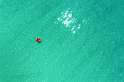 세이셸의 투명한 청록색 바다에서 수영 링 도넛에서 수영하는 슬림 한 여성의 공중 보기 소녀와 여름 바다 풍경 아름다운 파도 다채로운 물 드론에서 보기 공중 뷰에 대한 스톡