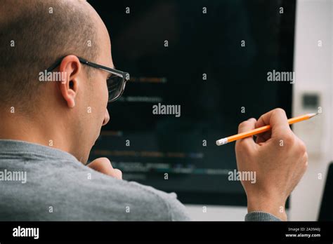 Programmer Working Behind The Desk Analysing Code On The Black Screen