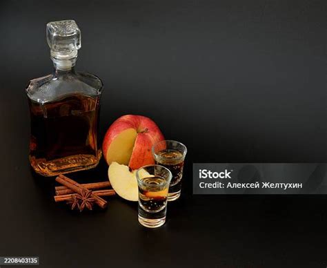 크리스탈 디켄터에 담긴 수제 사과 리큐어와 검은색 배경에 두 개의 잔 계피 스틱 아니스 별 잘 익은 과일 조각 옆에 0명에 대한 스톡 사진 및 기타 이미지 Istock