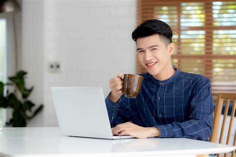 책상에 노트북 컴퓨터와 집에서 일하는 젊은 사업가 프리랜서 남성 은 통신을위해 노트북을 사용하여 집에 앉아 테이블에 휴식 신생 사업의 기업가 새로운 정상 가정 생활에 대한