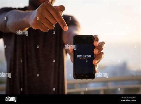 A Man Holds A Smartphone With The Amazon Logo Is An American Multinational Technology Company