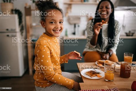 Portrait Of Girl Having Breakfast With Mother At Dining Table Stock