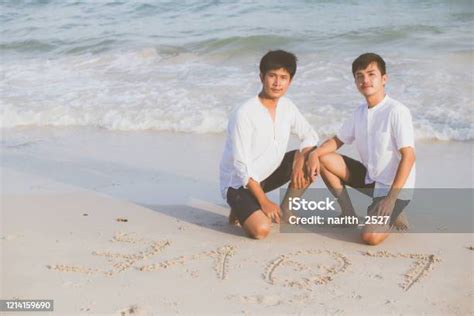 젊은 아시아 커플 게이 미소 로맨틱 그리기 단어 텍스트 사랑 함께 모래에 휴가 동성애 행복 하 고 재미 사랑 여행 여름에 해변에 모래에 앉아 Lgbt 법적 개념 2명에 대한