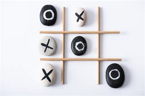 Top View Of Tic Tac Toe Game With Grid Made Of Paper Tubes And Pebbles Marked With Naughts And