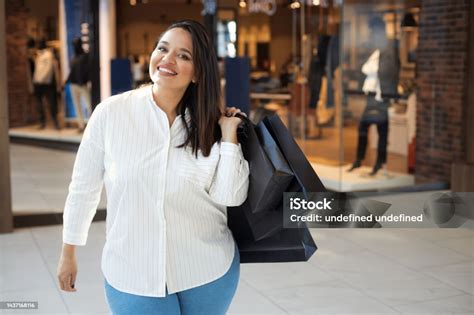 종이 봉지에 많은 구매가 있는 쇼핑몰의 캐주얼 과체중 여성 행복한 쇼핑 시간 배경 쇼케이스 옷 가게에 포즈를 취하는 웃는 플러스 사이즈 소녀 과체중에 대한 스톡 사진 및