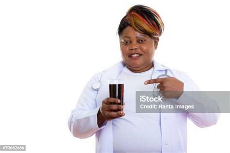 개최 하 고 소 다 음료의 유리에서 가리키는 동안 웃 고 행복 한 지방 검은 아프리카 여자 의사의 스튜디오 샷 30 39세에 대한 스톡 사진 및 기타 이미지 Istock