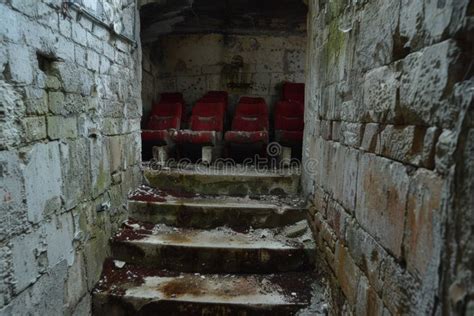 Abandoned Hall With Red Chairs And Crumbling Stone Walls Reveals A