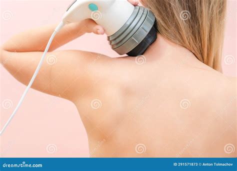 Rear View Of A Woman Using Massager For Neck And Shoulder Massage Stock