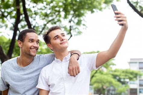 Amigos felizes de jovens estudantes do sexo masculino levando selfie Foto Grátis