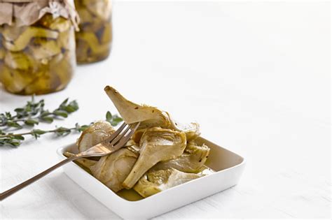 올리브 오일과 허브로 절인 아티초크 하트 테이블에 흰색 접시에 마늘과 절인 아티 초크 흰색 식탁보 수제 건강 식생활 기름 보존에 대한 스톡 사진 및 기타 이미지 Istock