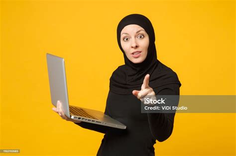 히 잡 검은 옷에 젊은 아라비아 무슬림 직원 여자 유지 및 작업 노트북 Pc 컴퓨터 노란색 벽 배경 스튜디오 초상화에 고립
