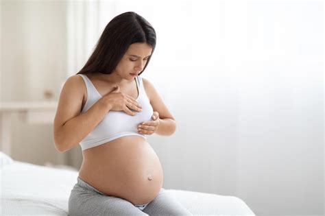 Premium Photo Pregnant Woman Sitting On Bed Massaging Her Breast