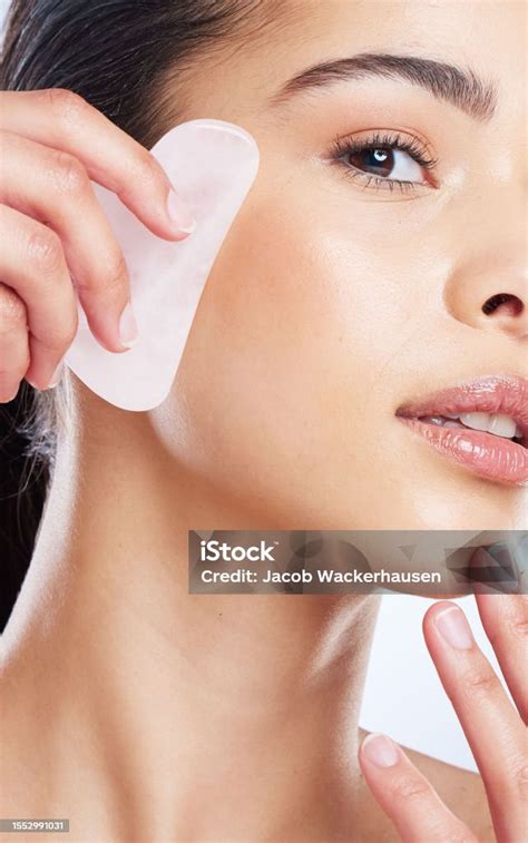Gua Sha 스킨케어 아시아 여성 초상화는 회색 배경에 노화 방지 화장품 또는 얼굴 마사지를 위해 스튜디오에 있습니다 로즈 쿼츠 얼굴 및 여성 웰빙 모델로 고급스러움