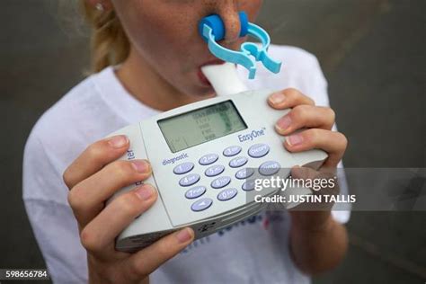 A Girl Blows Into A Spirometer During A Photocall To Promote Clean
