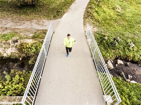 Aerial View Of A Runner Running Across Bridge In Park On A Jogging Path