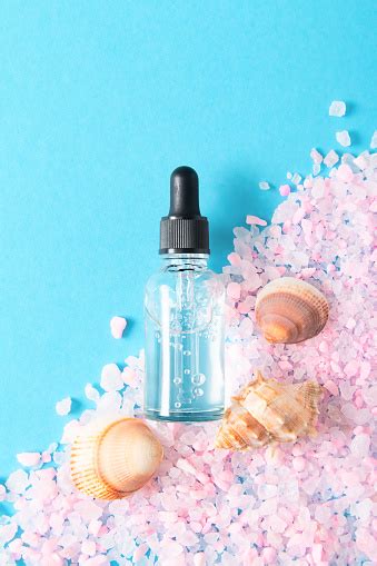 드롭퍼 투명 유리 화장품 병 모의 분홍색 바다 소금과 파란색 배경에 조개 친환경 케어 유기농 제품 뷰티 트리트먼트 스파 컨셉 공간을 복사합니다 0명에 대한 스톡 사진 및