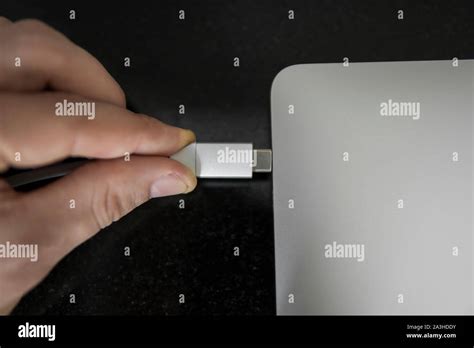 Male Hand Plugging White USB C Type C Cable Into A Port On A Grey Laptop Notebook Computer USB