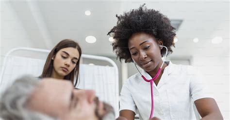 아프리카 계 미국인 여성 의사와 함께 아픈 남자 환자는 병원 응급실에서 청진기로 가슴을 듣습니다 의사와 간호사가 병실에서 노인 환자를 방문합니다 사진 Unsplash