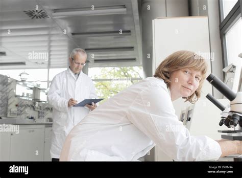 Scientists Working In Laboratory Woman With Microscope And Man Taking