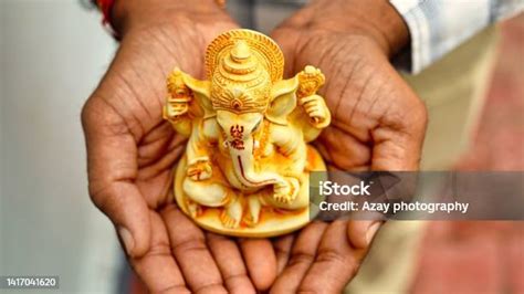비사르얀 또는 몰입을 위해 손바닥 배경에 가네샤 우상을 들고 있는 손 주 가나파티 우상 태양 광선과 함께 가네쉬 차투르티 힌두교 축제 기간 동안 연례 의식 라자스탄 인도의