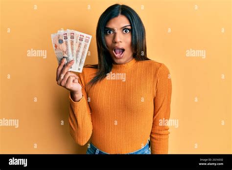 Young Latin Transsexual Transgender Woman Holding 10 United Kingdom Pounds Banknotes Scared And