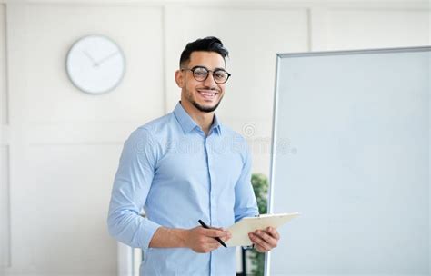 arab male teacher standing near empty blackboard giving remote lecture