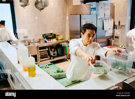 Male Chef Passing Broccolini Container While Working In Commercial